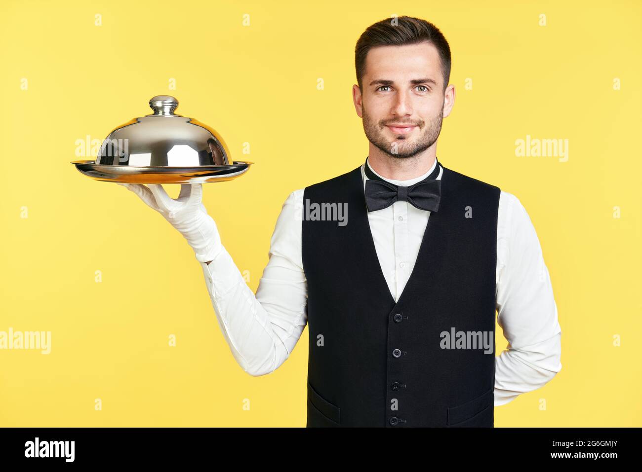 Handsome elegant waiter holding tray and cloche ready to serve on ...