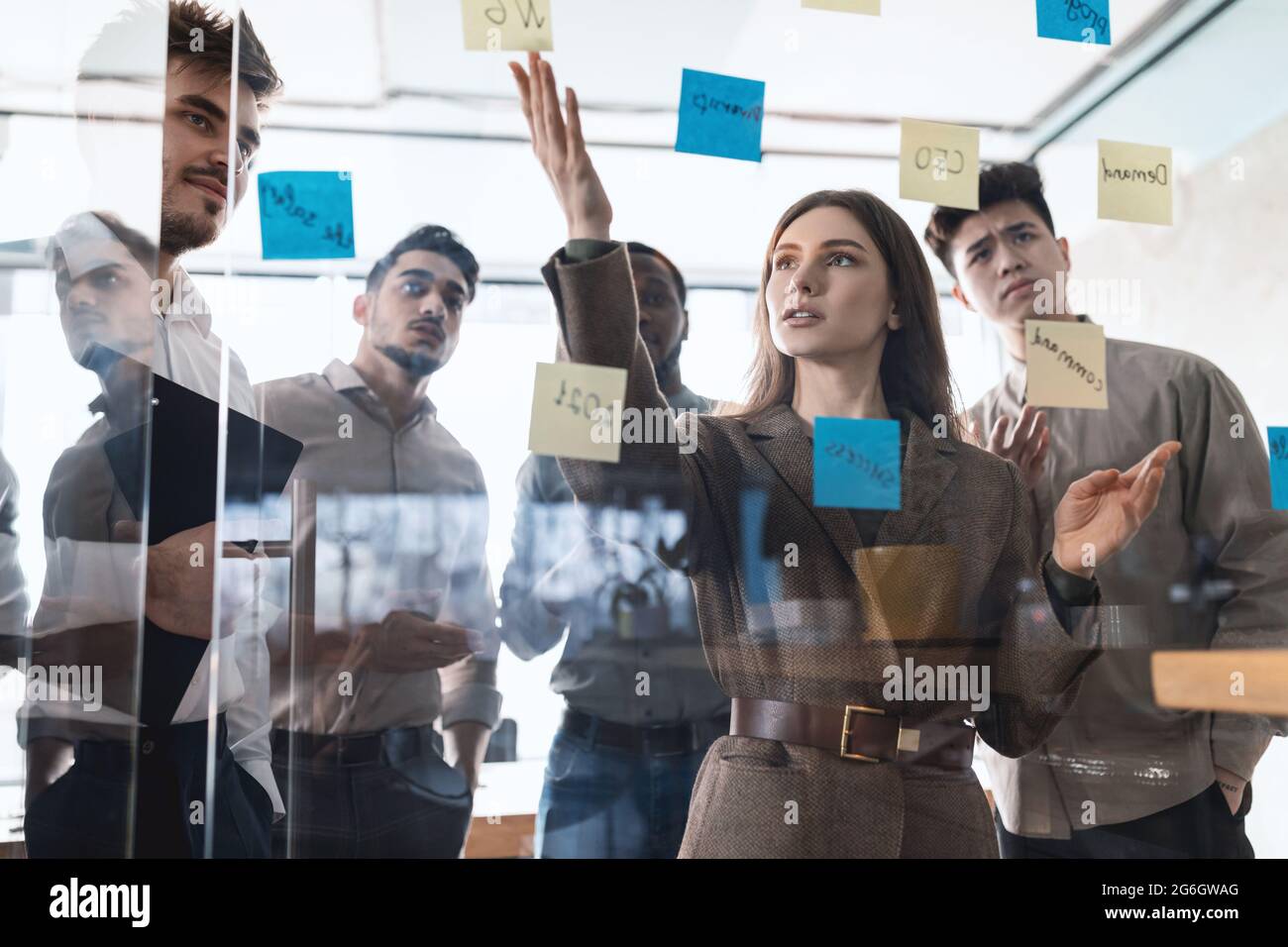 Colleagues brainstorming using sticky post-it notes on glass wall Stock ...