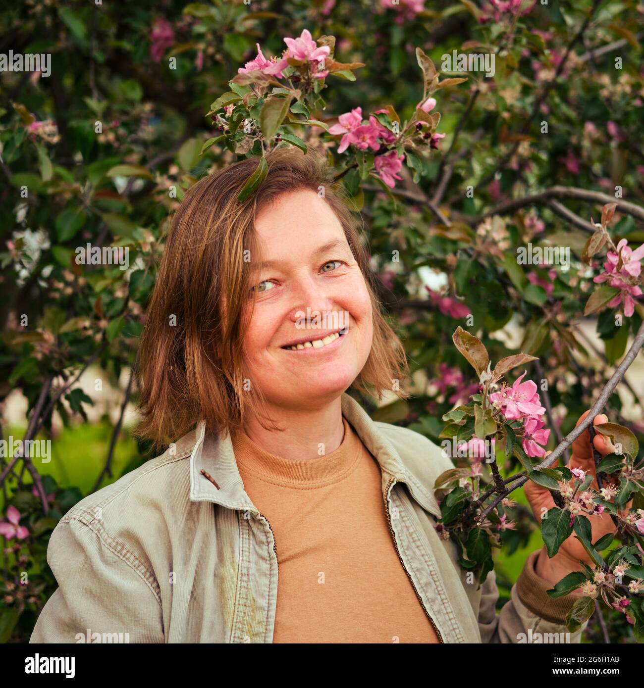 Happy adult woman on background of blooming spring tree in park Stock ...