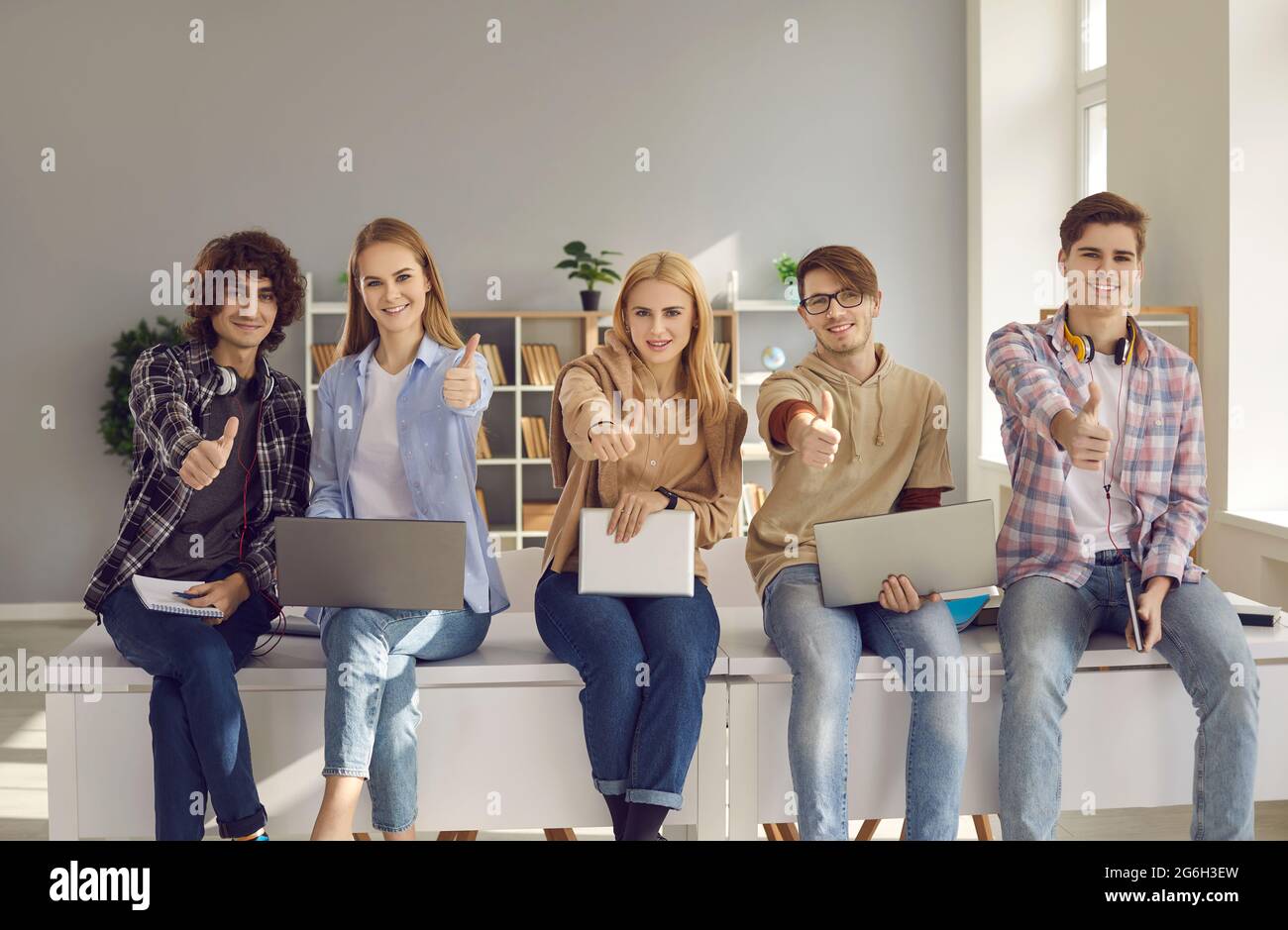 Group of happy college students with laptops and tablets smiling and ...