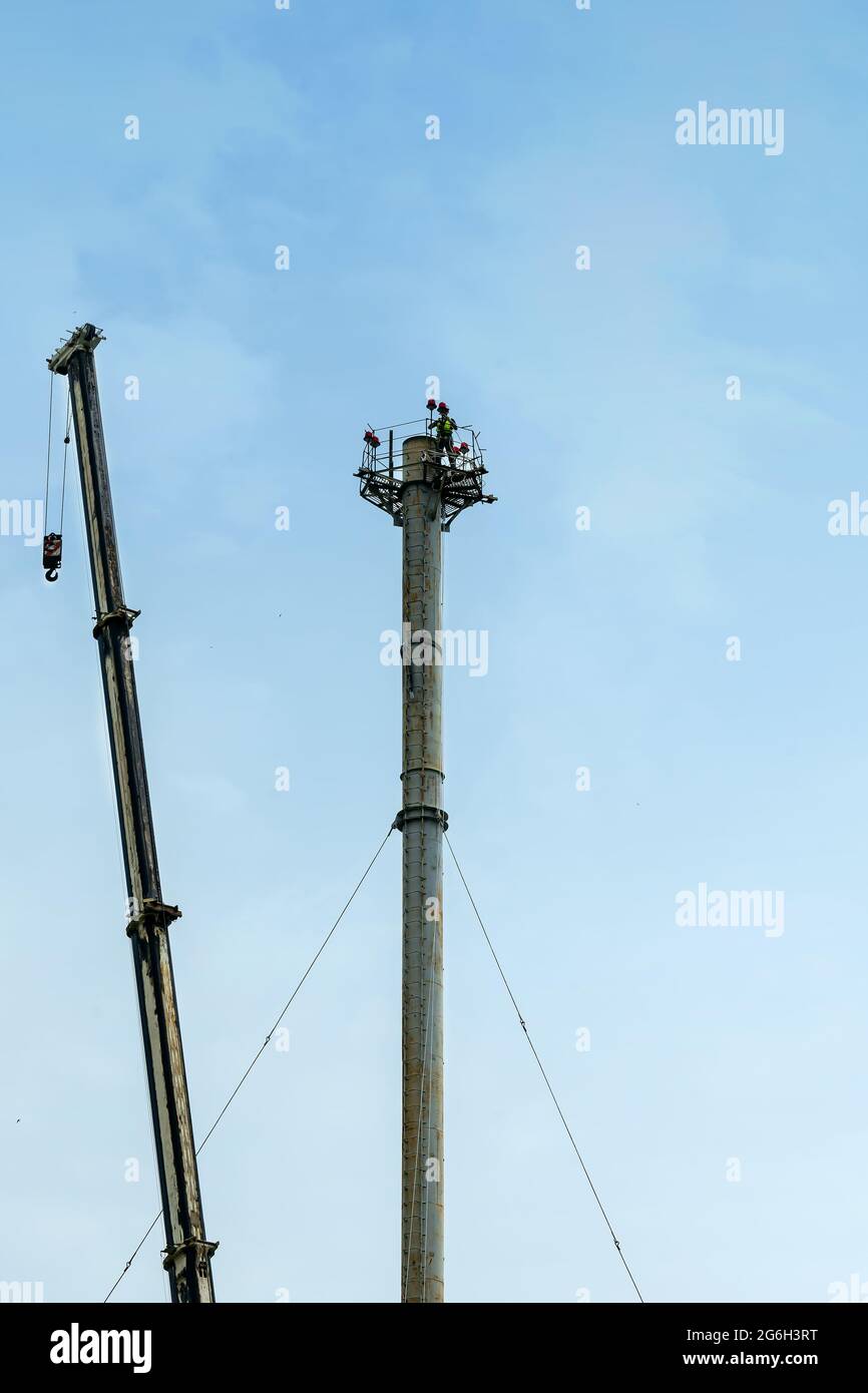 Tall metal pipe and mobile crane against the sky. Preparatory work for ...