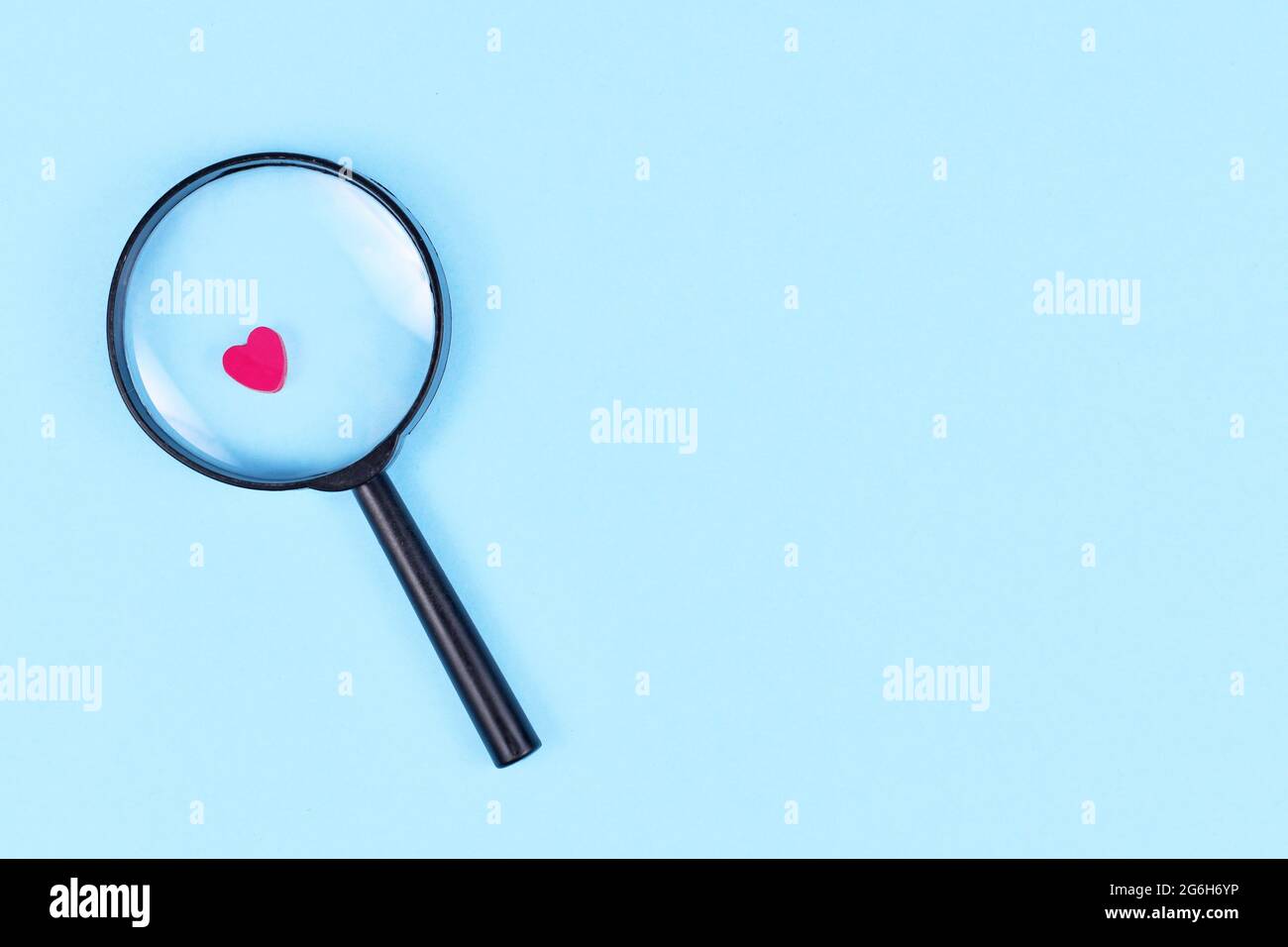 Looking for love concept with magnifier glass and pink heart icon on ...