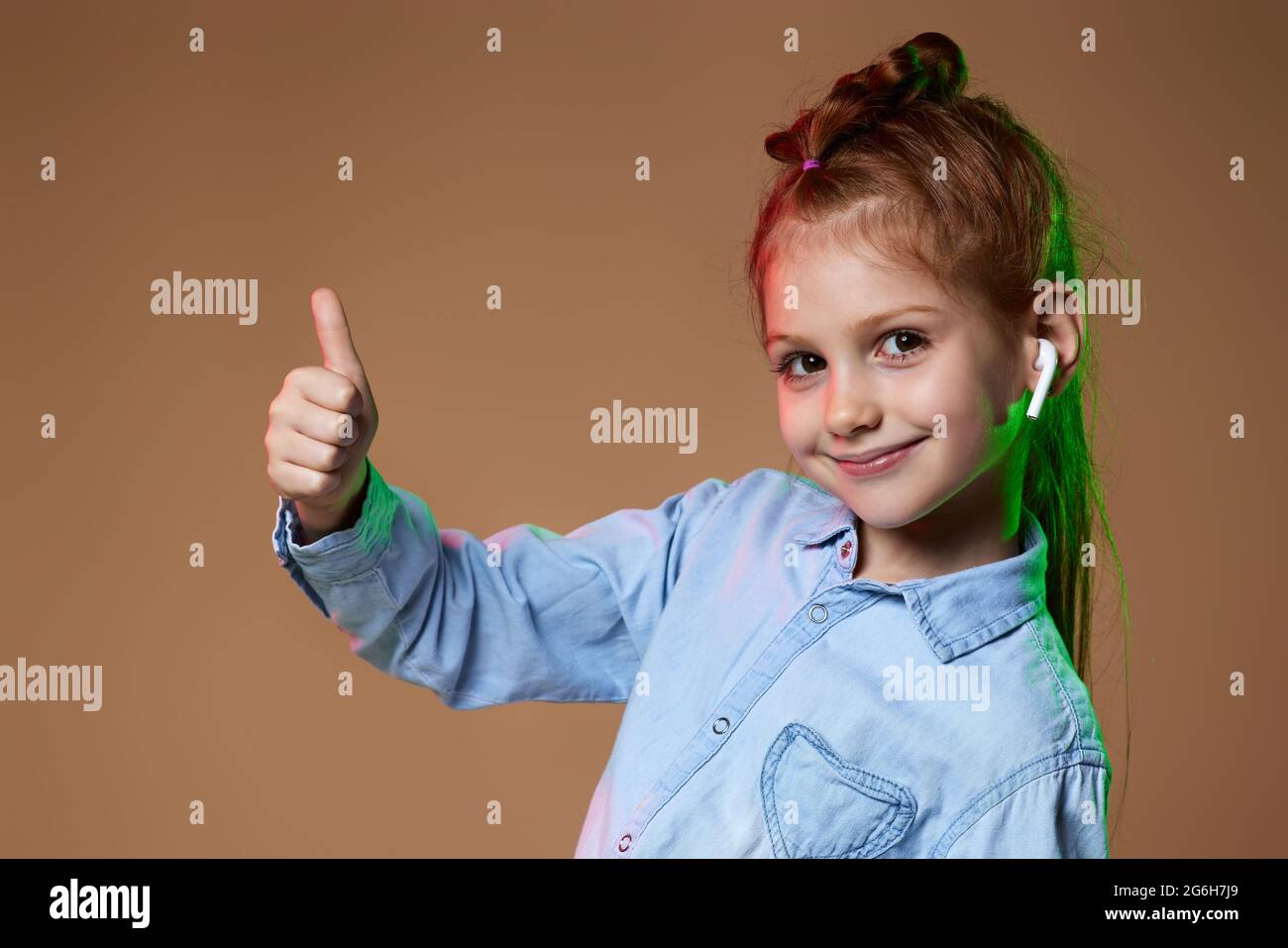 happy redhead child girl in earphones listening to music on beige ...