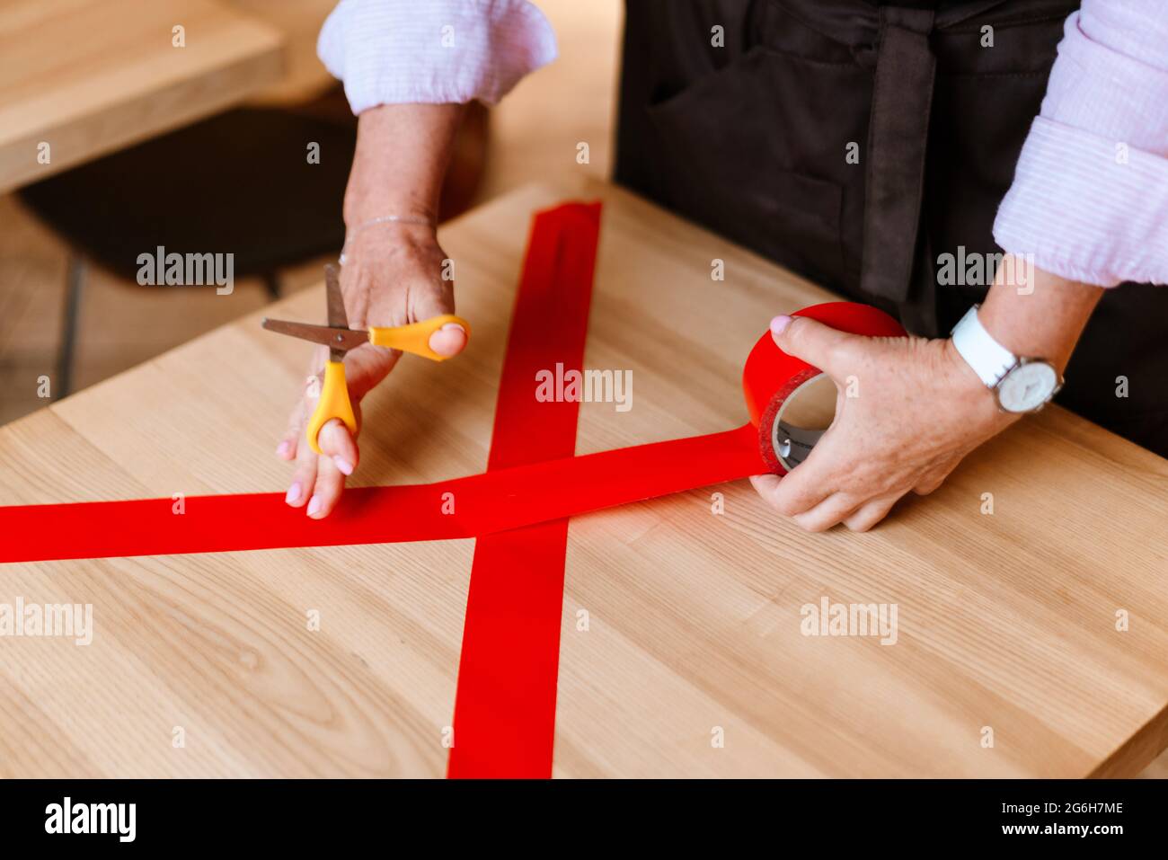 Mature woman using adhesive tape for marking of table in cafe Stock ...