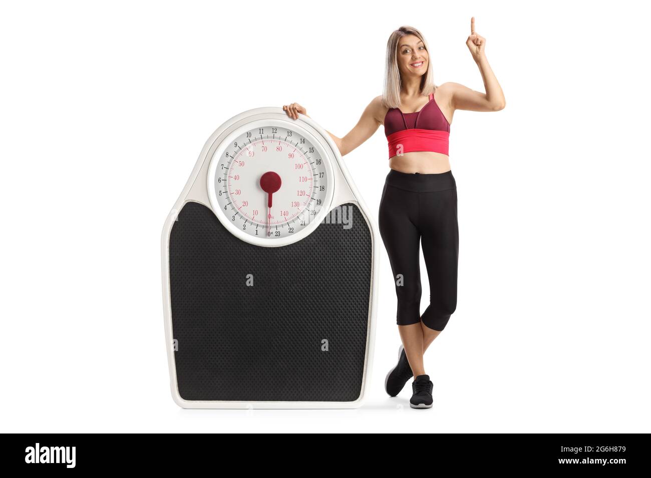 Full length portrait of a young woman in sportswear leaning on a big ...