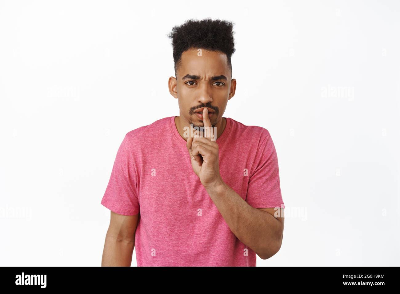 Dont speak. Serious african american guy hushing, hold finger near lips ...