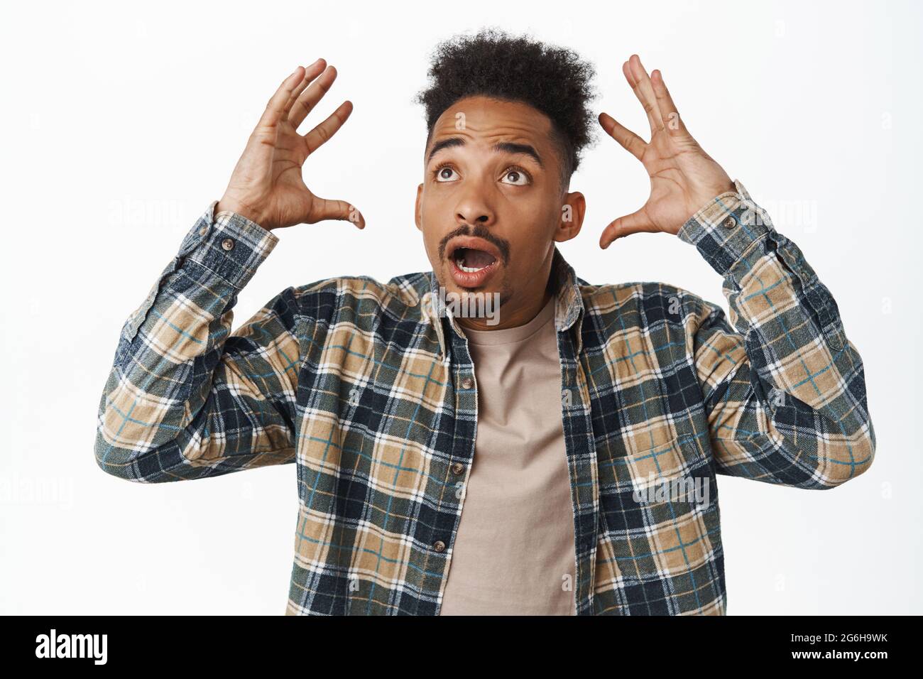 Shocked and excited african american guy, holding hands near head ...