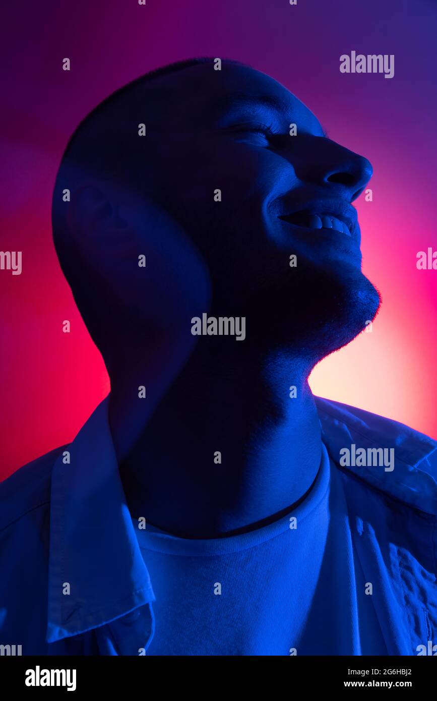 Cinematic portrait of handsome young man in neon blue pink lighted room ...