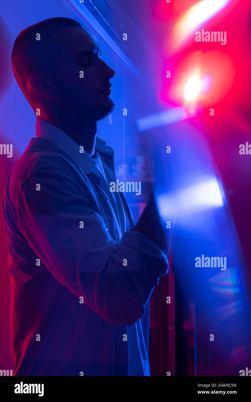 Cinematic portrait of handsome young man in neon blue pink lighted room ...