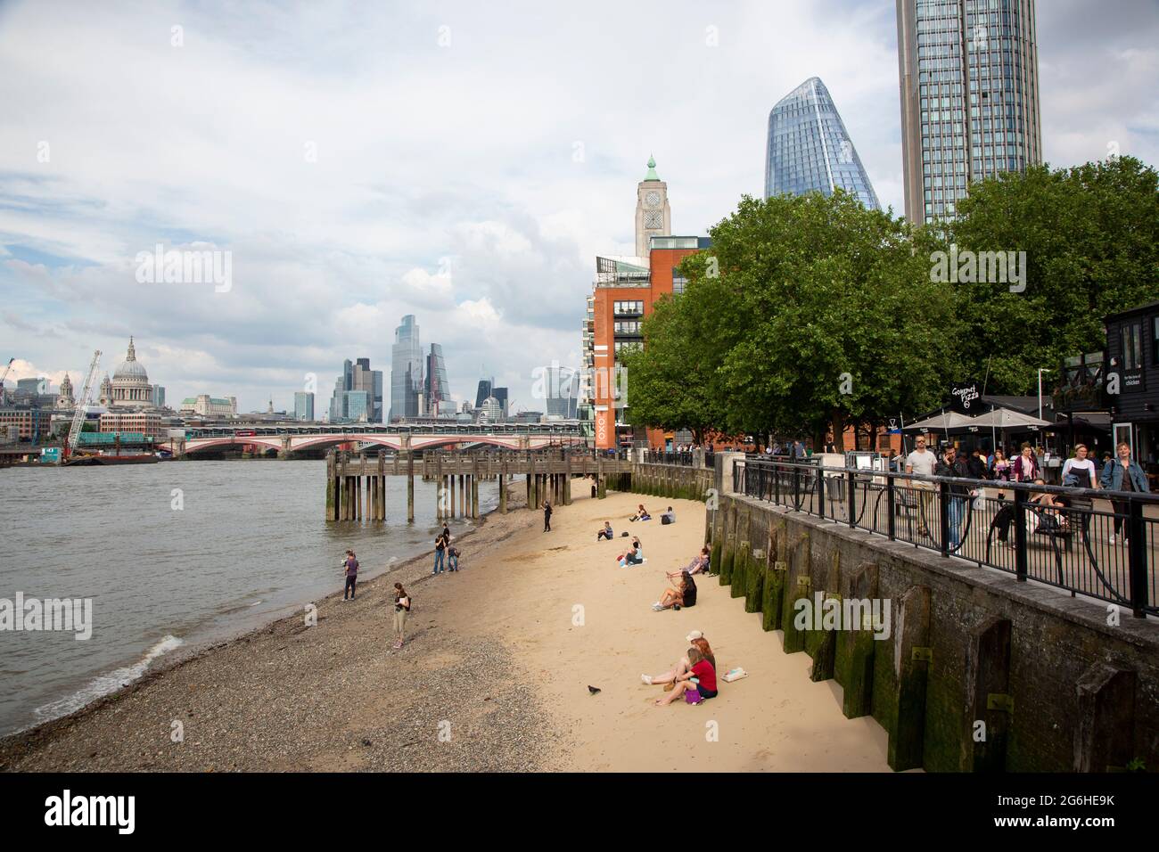People enjoying the sunny weather on the Thames Beach on the river's ...