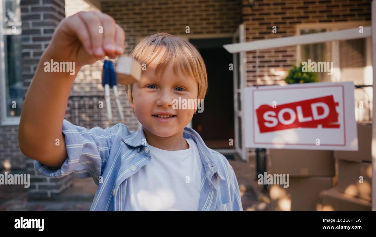 joyful boy looking at camera and holding keys near new house Stock ...