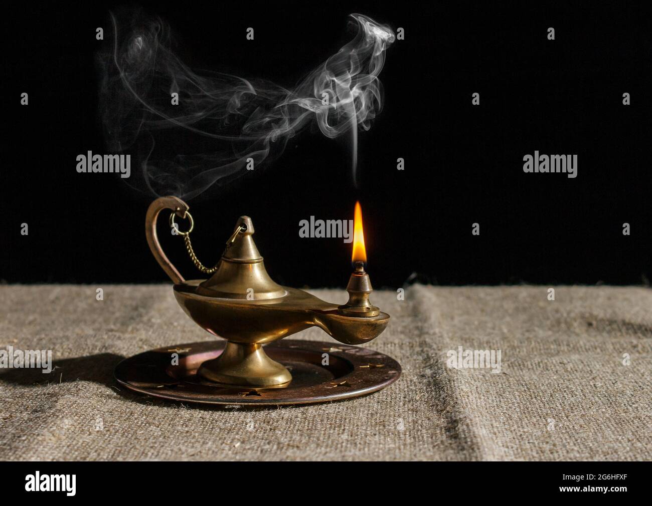 burning magic lamp of aladdin on table. indoor closeup on black ...