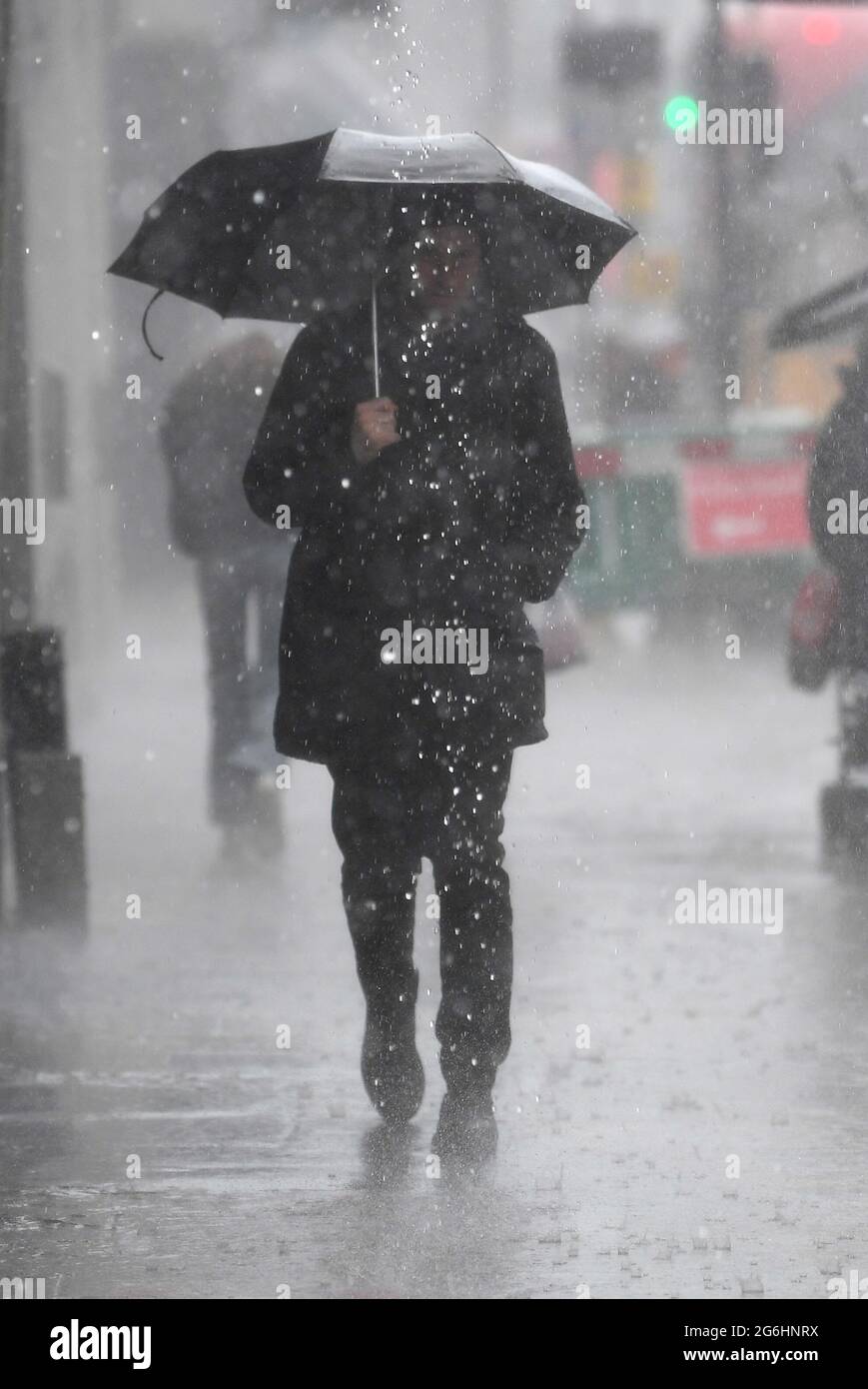 A man walking in a rain shower in east London. Picture date: Tuesday ...