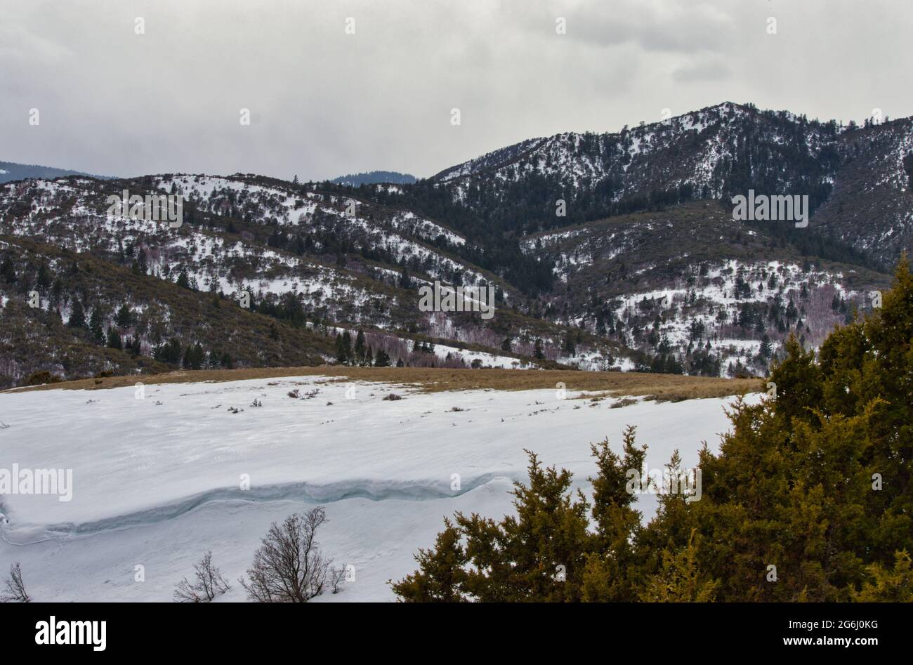 Scenic view of mountains and fields enveloped in the snow on a cloudy ...