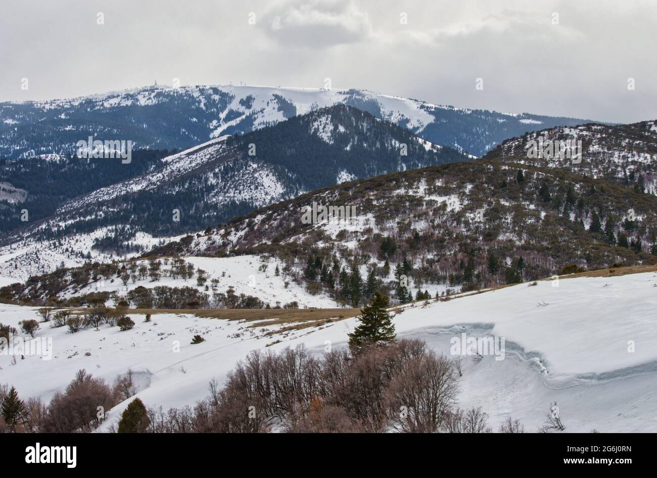 Scenic view of mountains and fields enveloped in snow on a cloudy sky ...