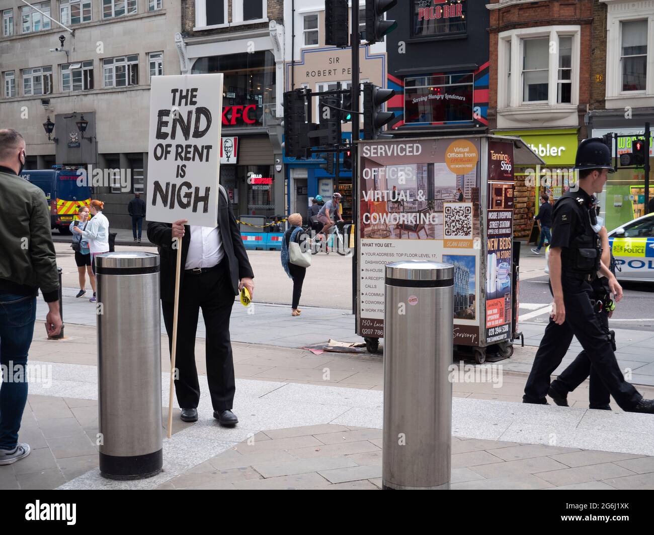 man with suit and bowler hat holding placard with, the end of rent is ...