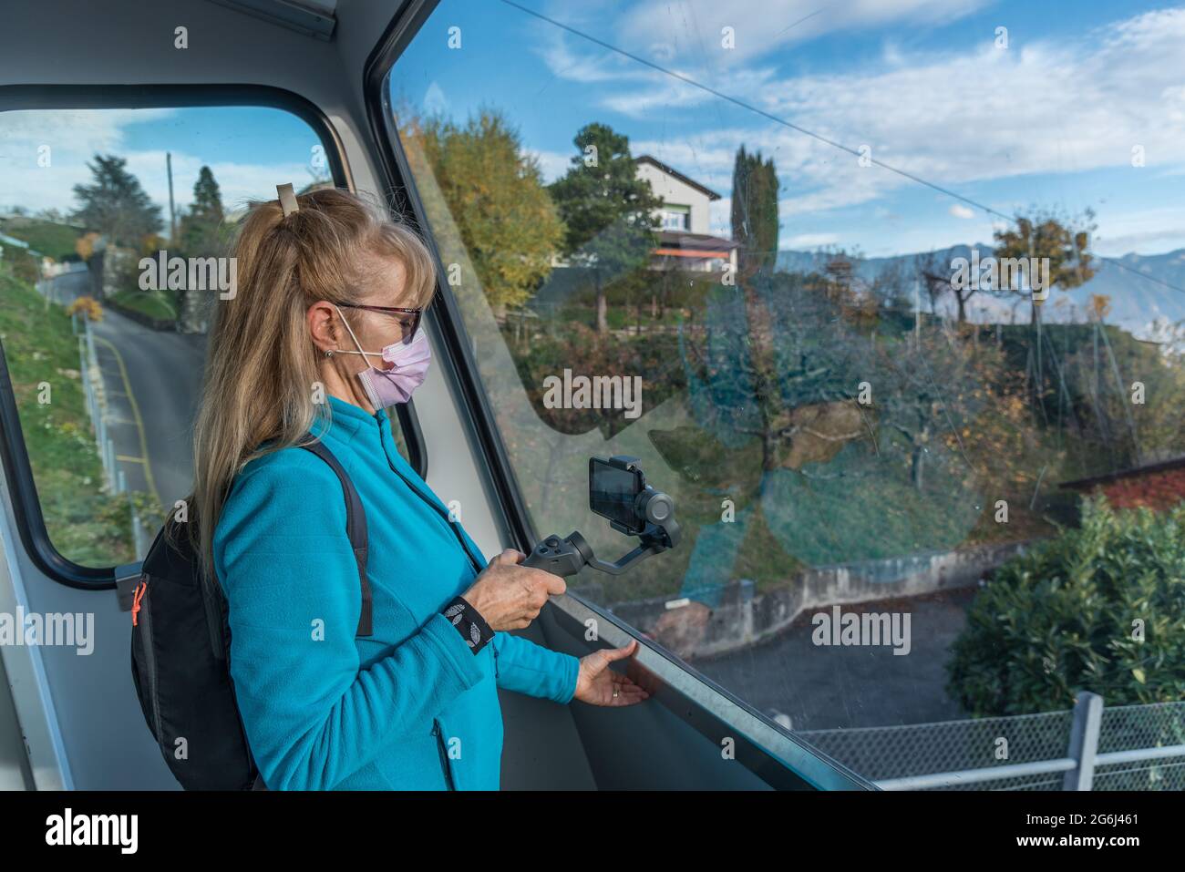 Happy woman in face mask due to covid19 recording her trip in funicular ...