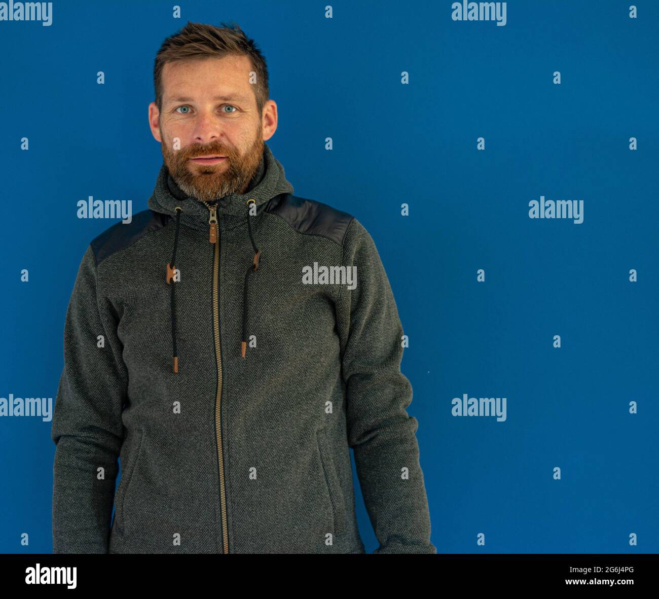 young man in jacket with blue background Stock Photo - Alamy