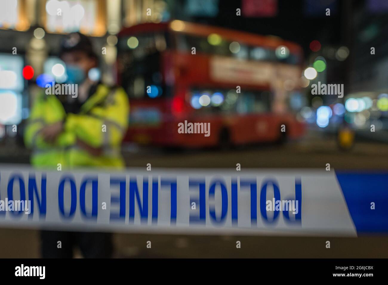 A police officer stands inside the perimeter of a crime scene in London ...