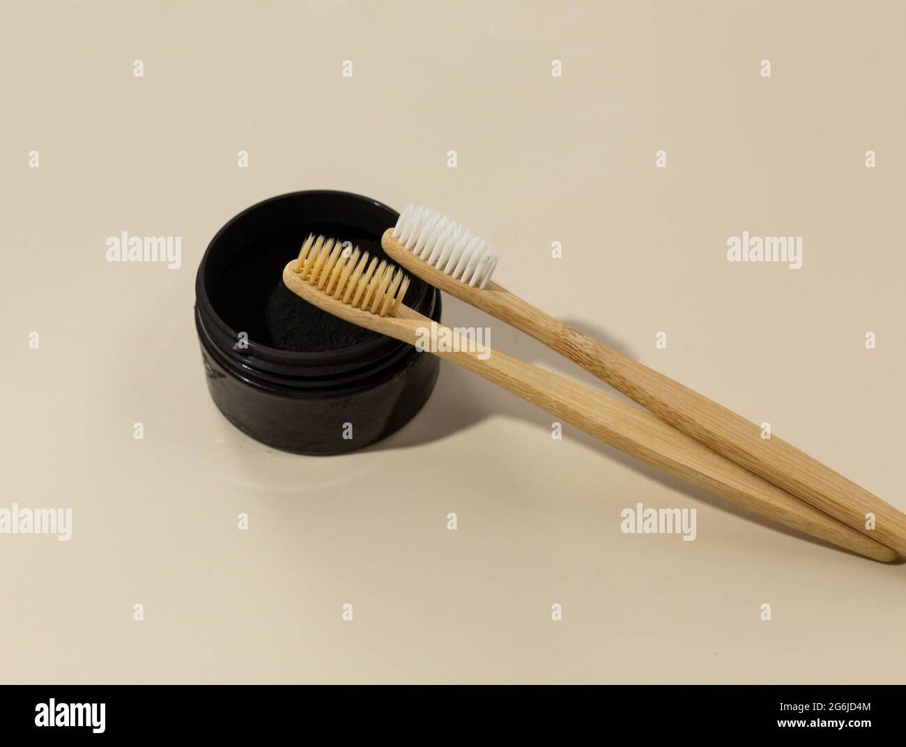 A set of eco-friendly bamboo toothbrushes and black tooth powder on a ...