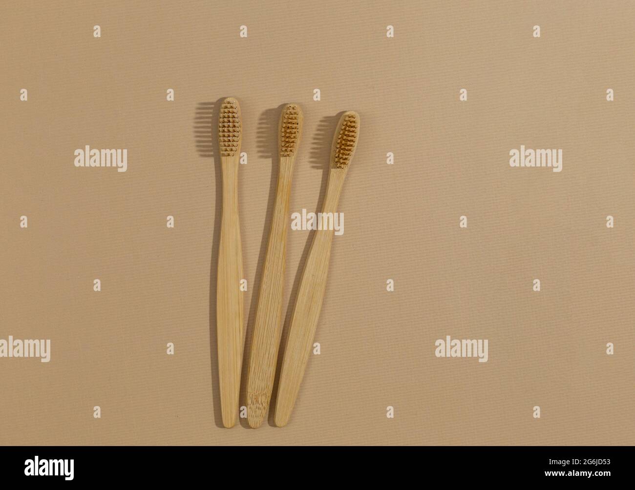 A set of eco-friendly bamboo toothbrushes on a beige pastel background ...