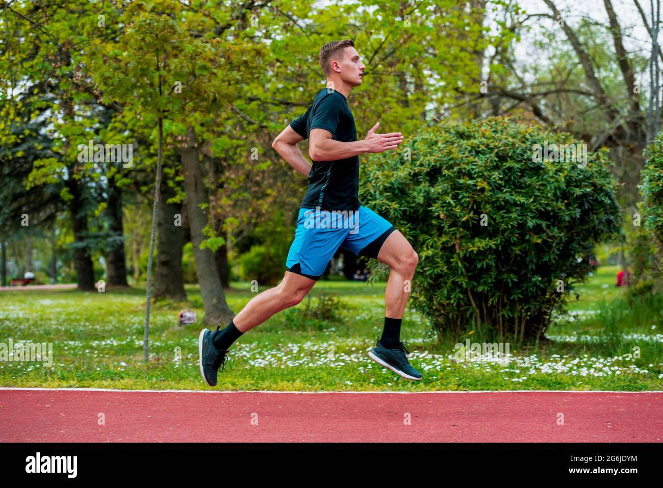 Young attractive man running on racetrack during training session. Male ...