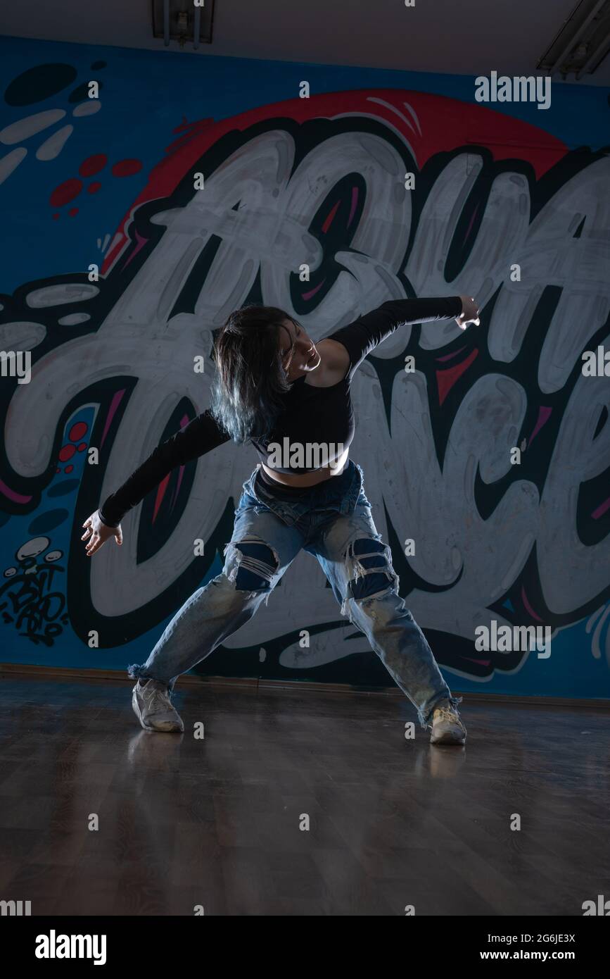 Female dancer in activewear squatting on the floor of modern dance ...