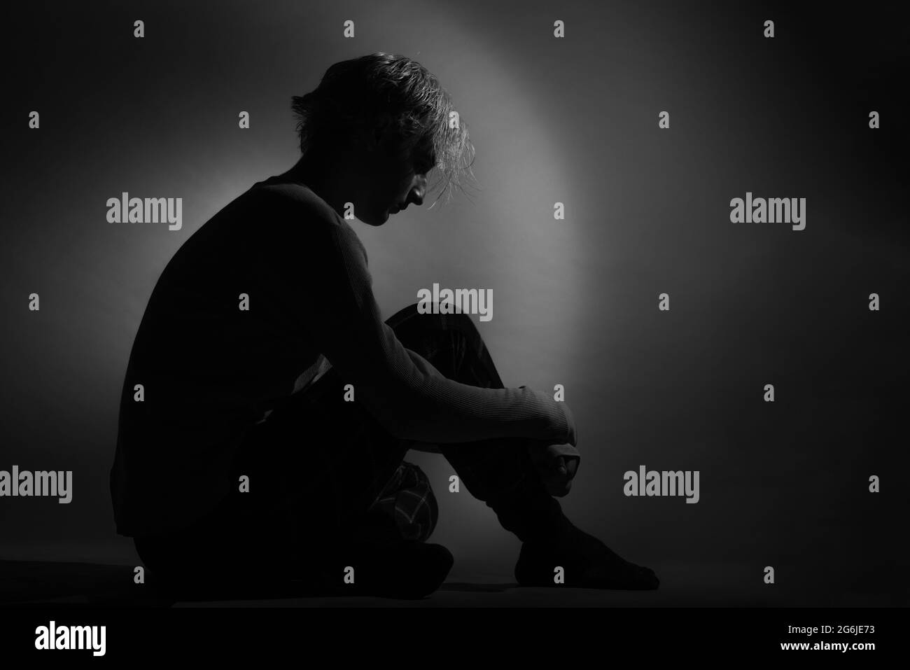 Silhouette os sad boy sitting on the ground while hugging his leg Stock ...