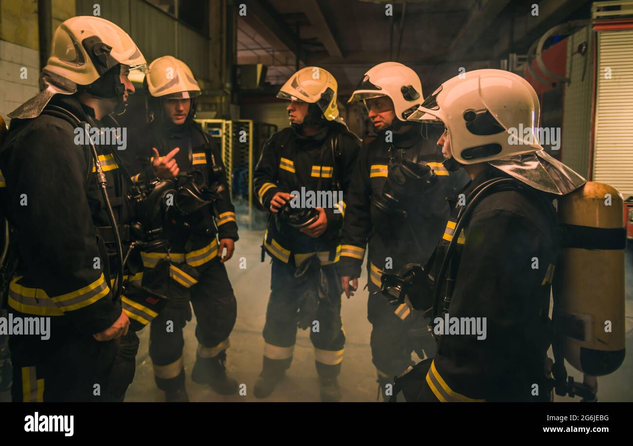 Group of firefighters with uniform inside the fire station preparing ...