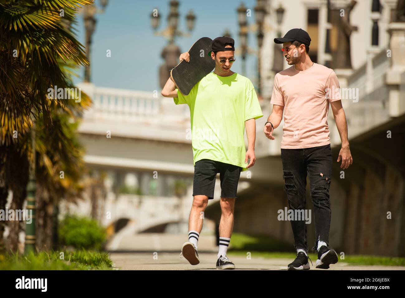 Two fit male friends are walking together while discussing something ...