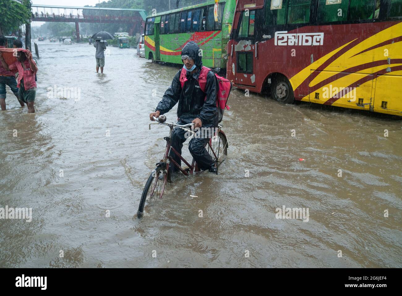 A man delivering food rides through rain water on his bicycle along ...