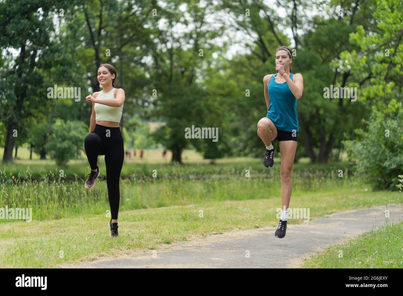 Two attractive girls are jumping while running together Stock Photo - Alamy