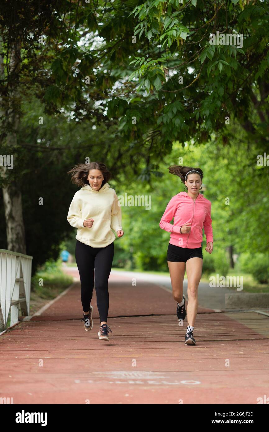 Two attractive girls are running together in the morning on their track ...