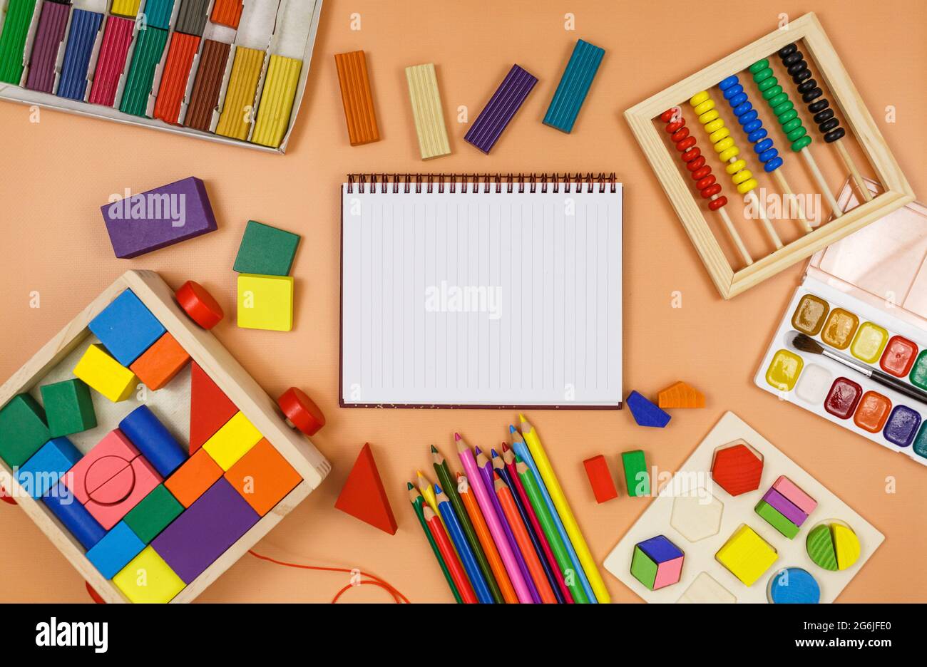 Colorful cubes, paints, pencils, blocks, modeling clay on orange ...