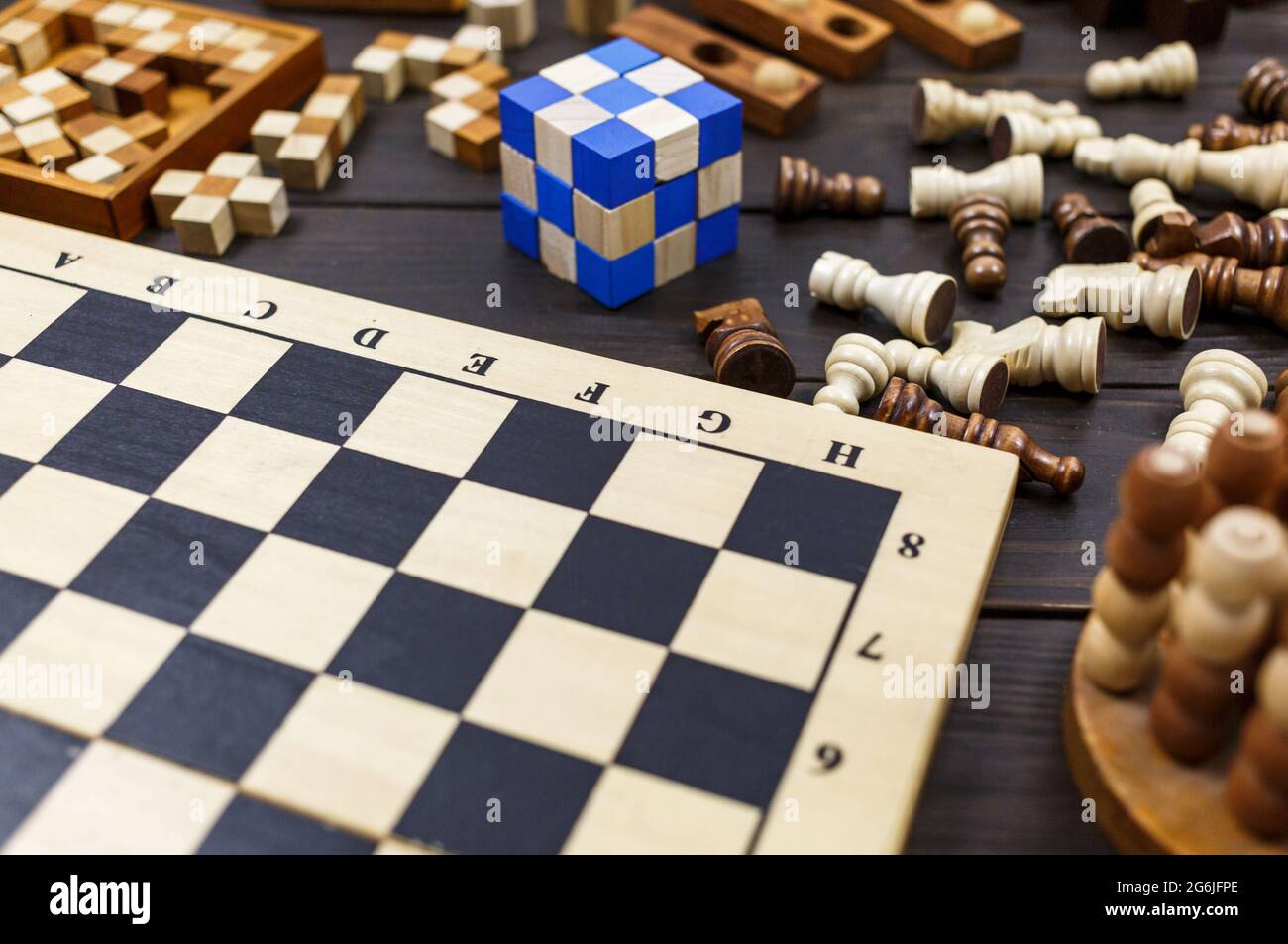 Chessboard and chess figures, wooden cubes, puzzle games on dark wooden ...