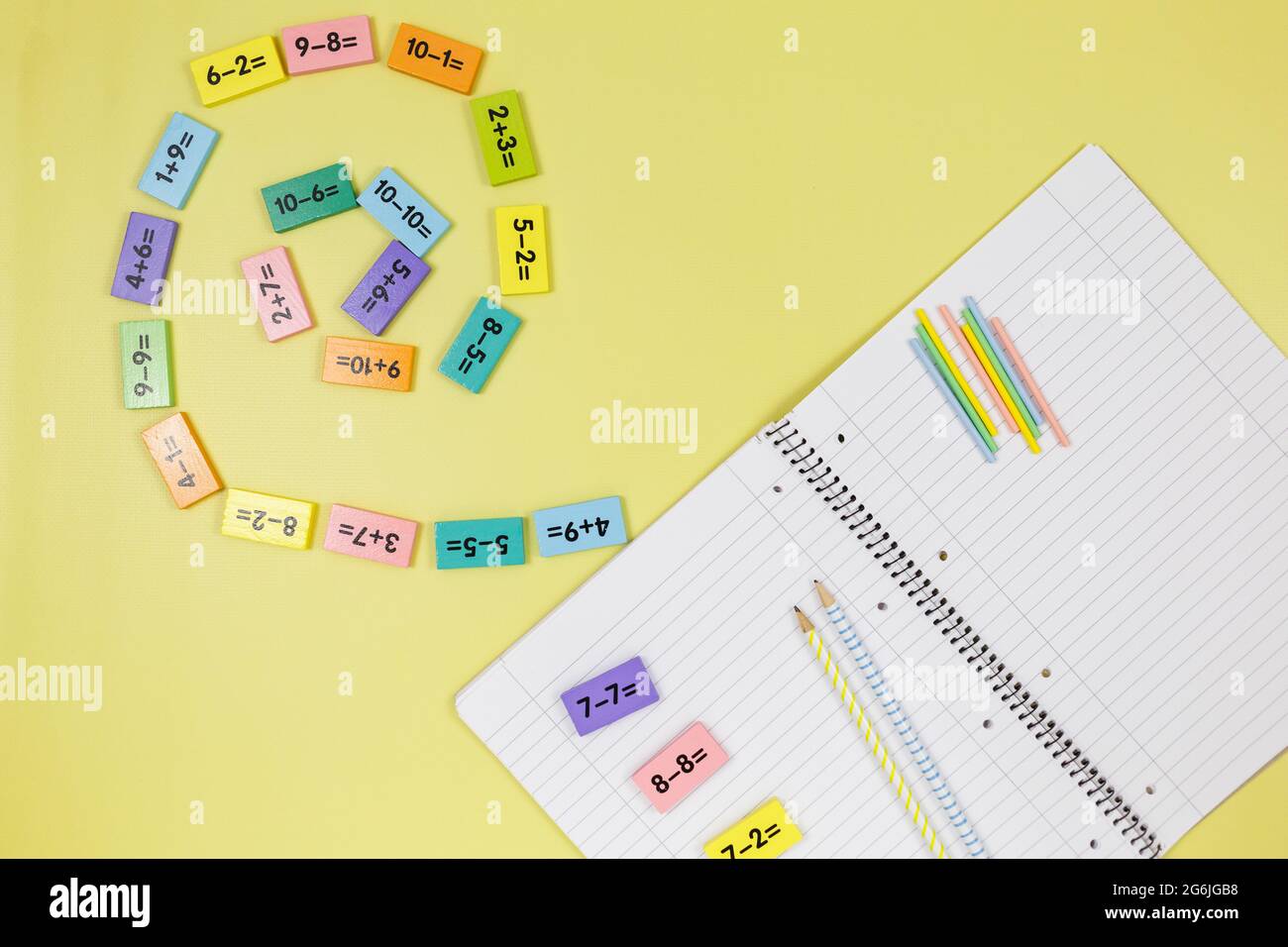 Open notebook, pencils and mathematical examples on yellow background ...