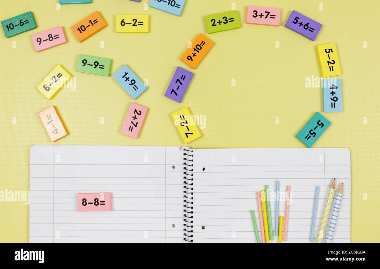 Open notebook, pencils and mathematical examples on yellow background ...