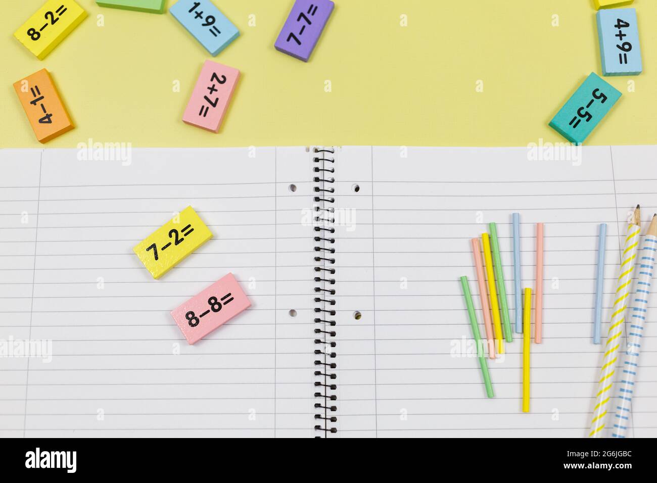 Open notebook, pencils and mathematical examples on yellow background ...