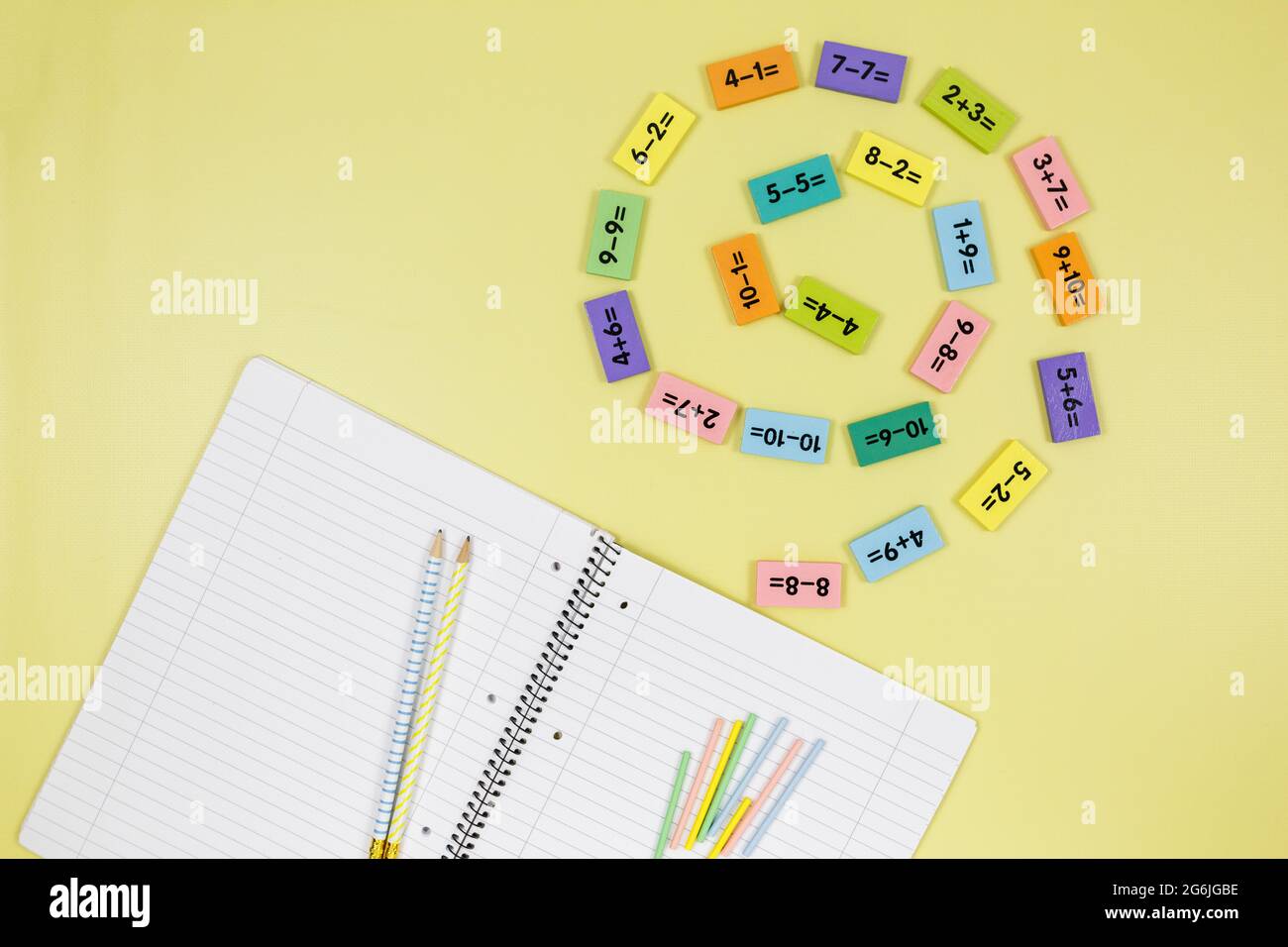 Open notebook, pencils and mathematical examples on yellow background ...