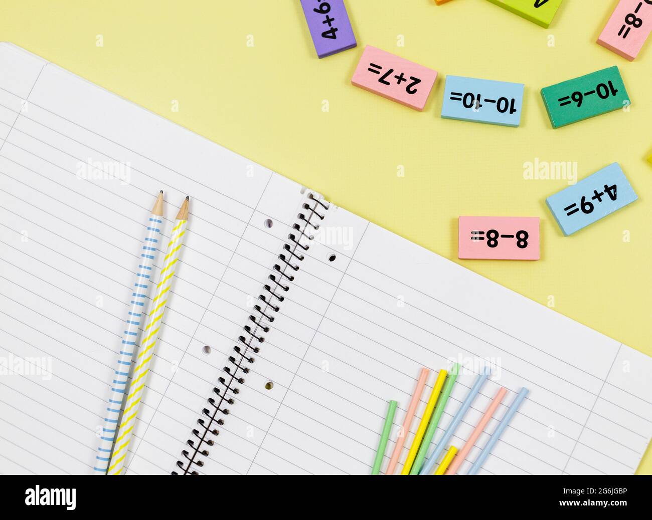 Open notebook, pencils and mathematical examples on yellow background ...