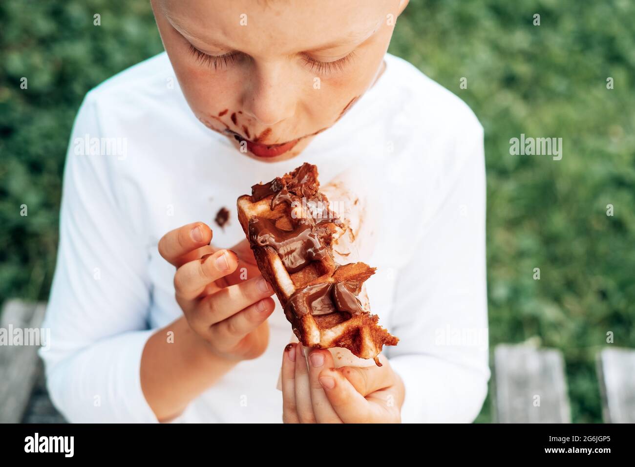 The child eating a Belgian waffle with a chocolate topping.top view ...
