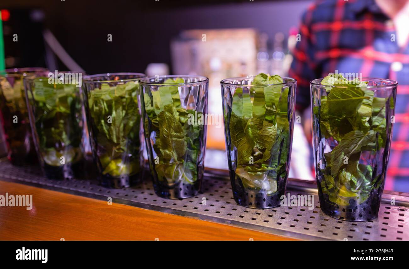 Bartender putting lime into glass. Muddling lime to make a cocktail ...