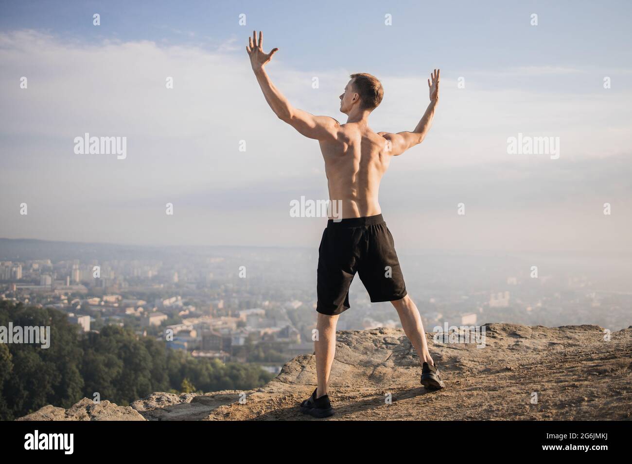 Back view of muscular young man in sport clothes standing with arms ...
