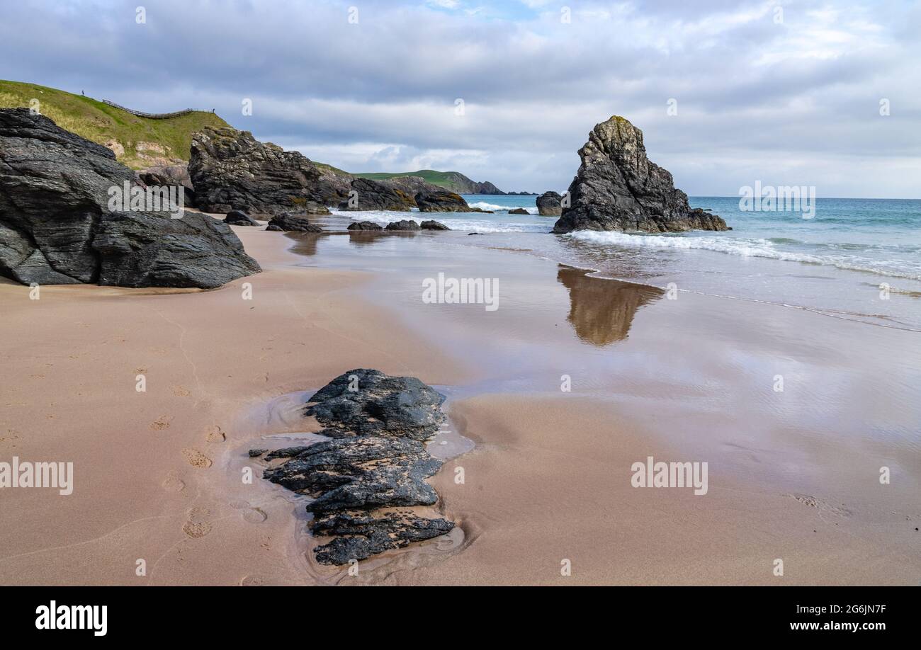 Reflections of a rock in the incoming tide on a sandy beach Stock Photo ...