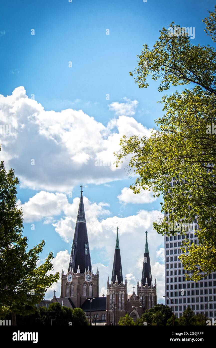 Spires of Tulsa with modern and older buildings framed by trees under a ...