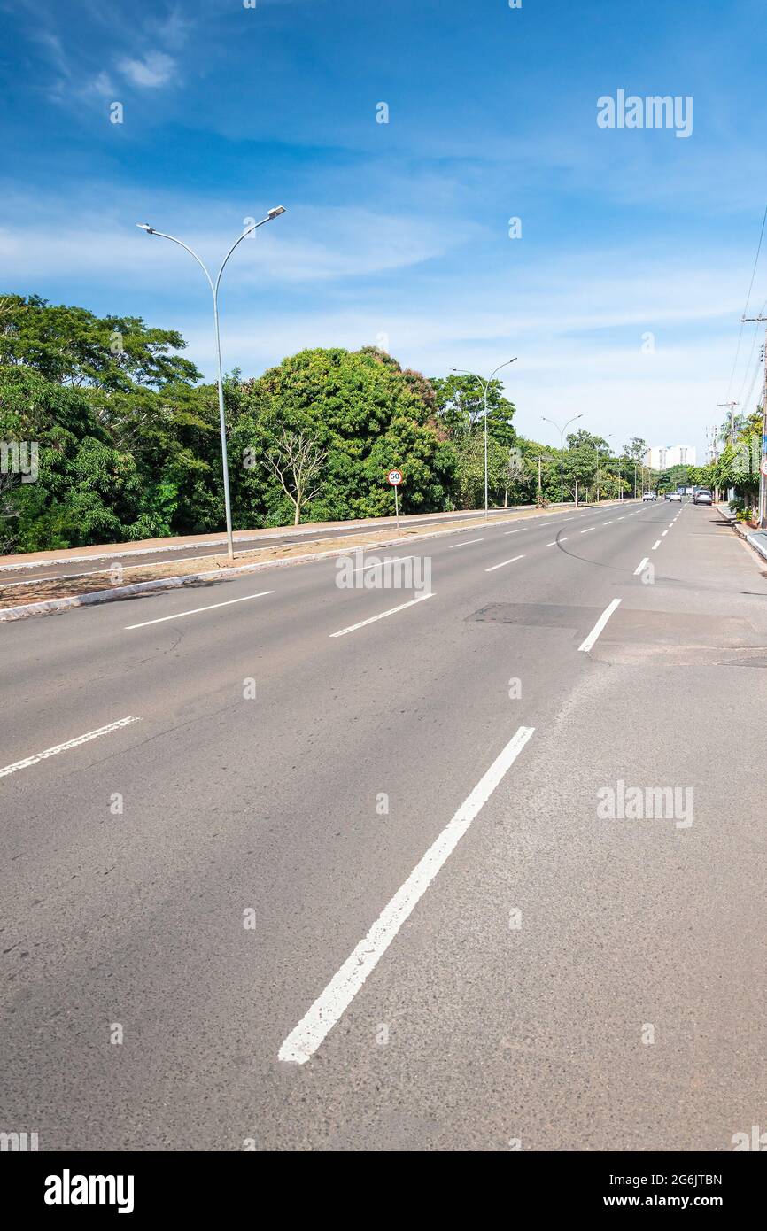 Large avenue with a separated bike lane and green trees around. Nelly ...