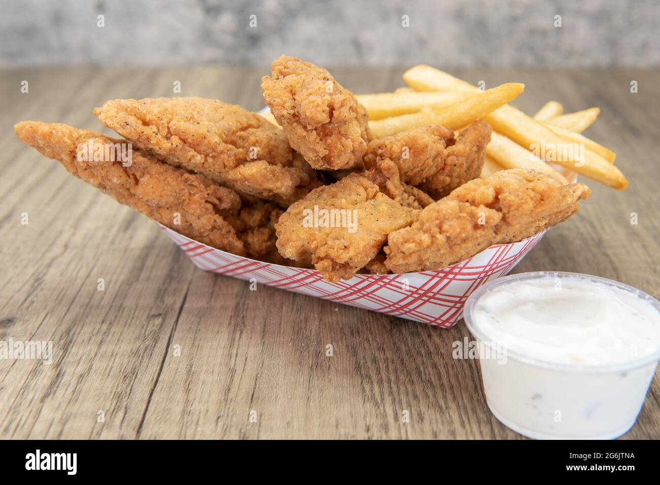 Deep fried meal of strips of breaded chicken and a side order of french ...