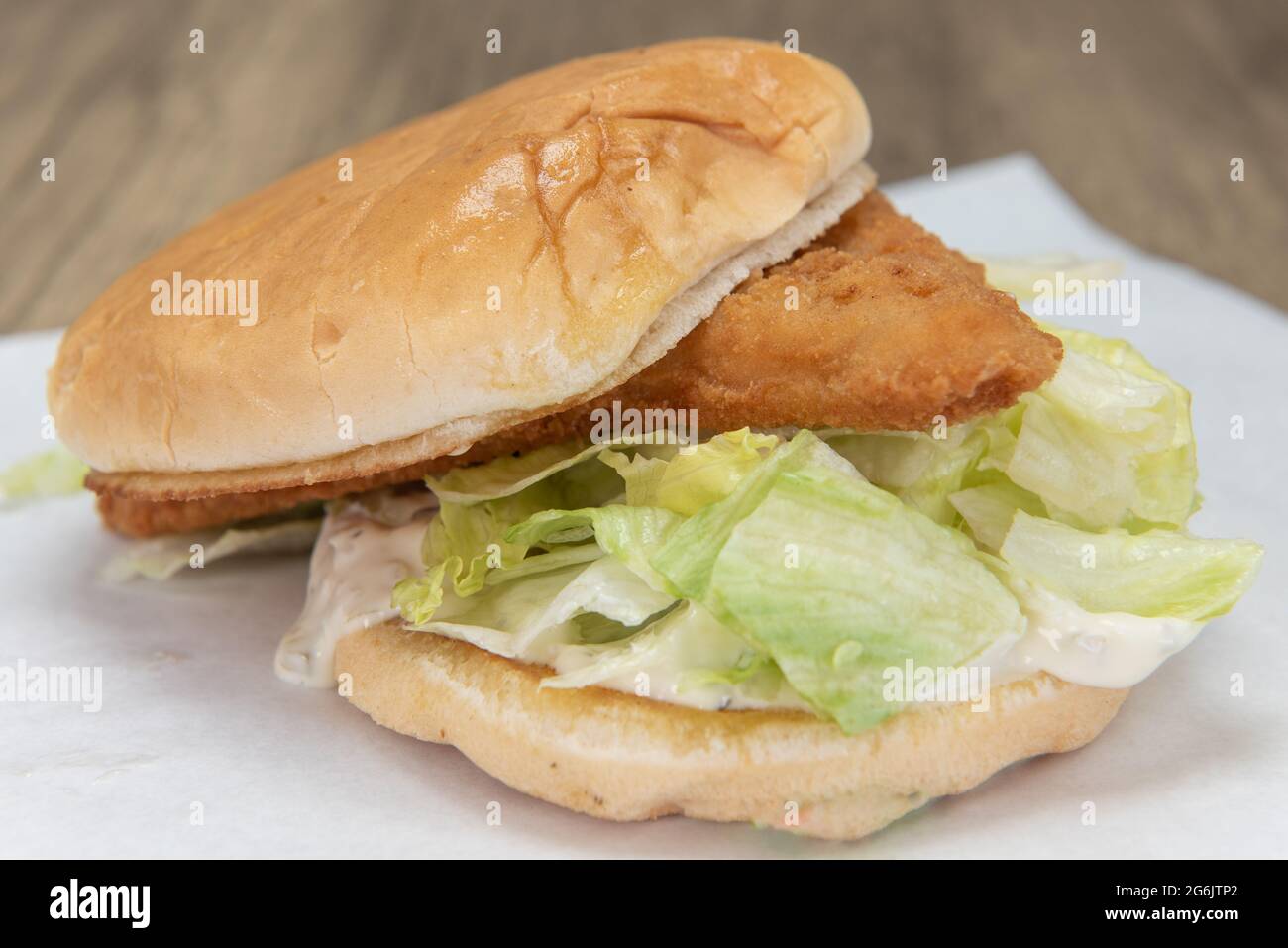 Hearty fish sandwich with breaded fillet on a bed of lettuce and ...