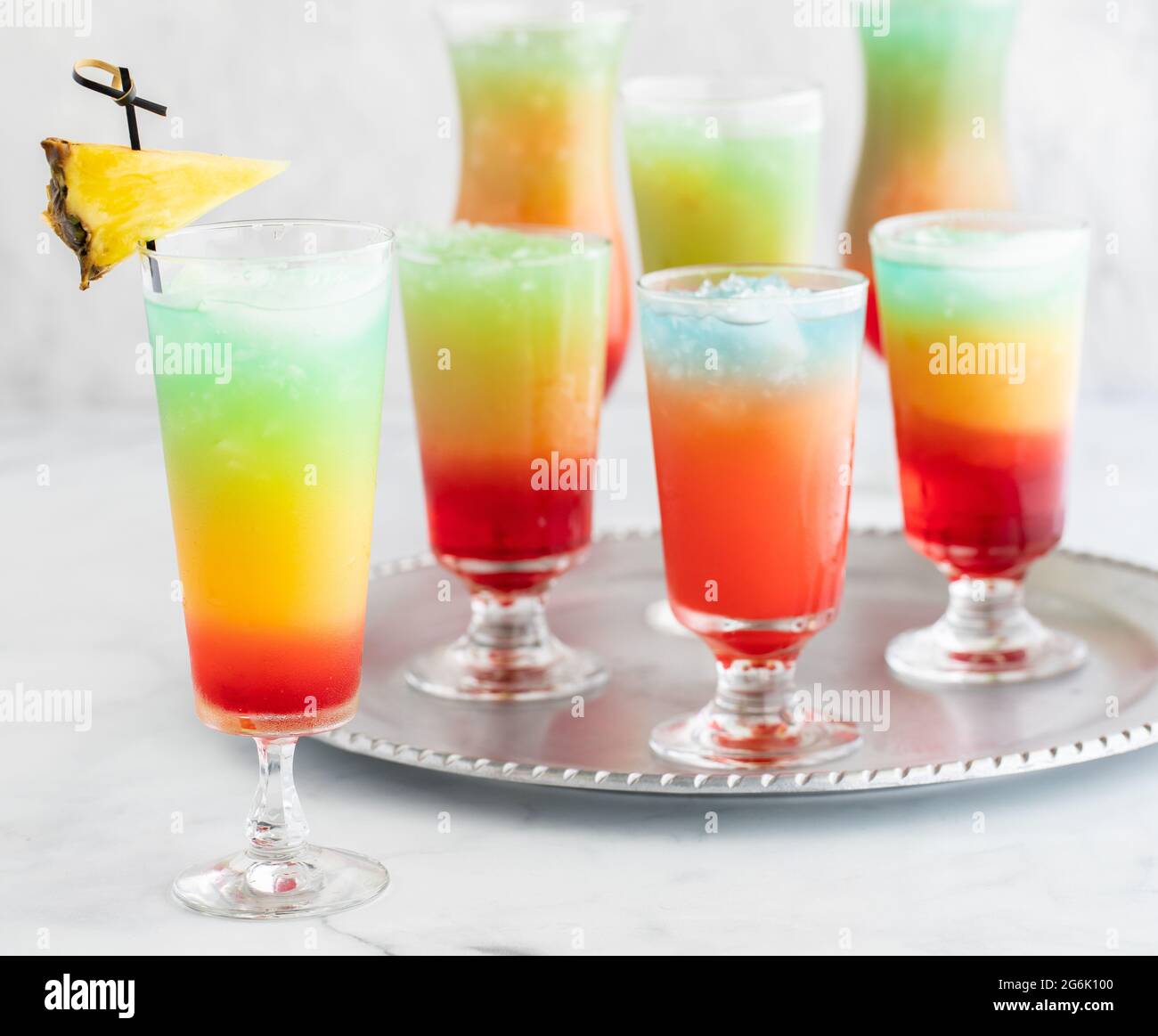 A tray of frosty colourful mocktails with one garnished mocktail in ...