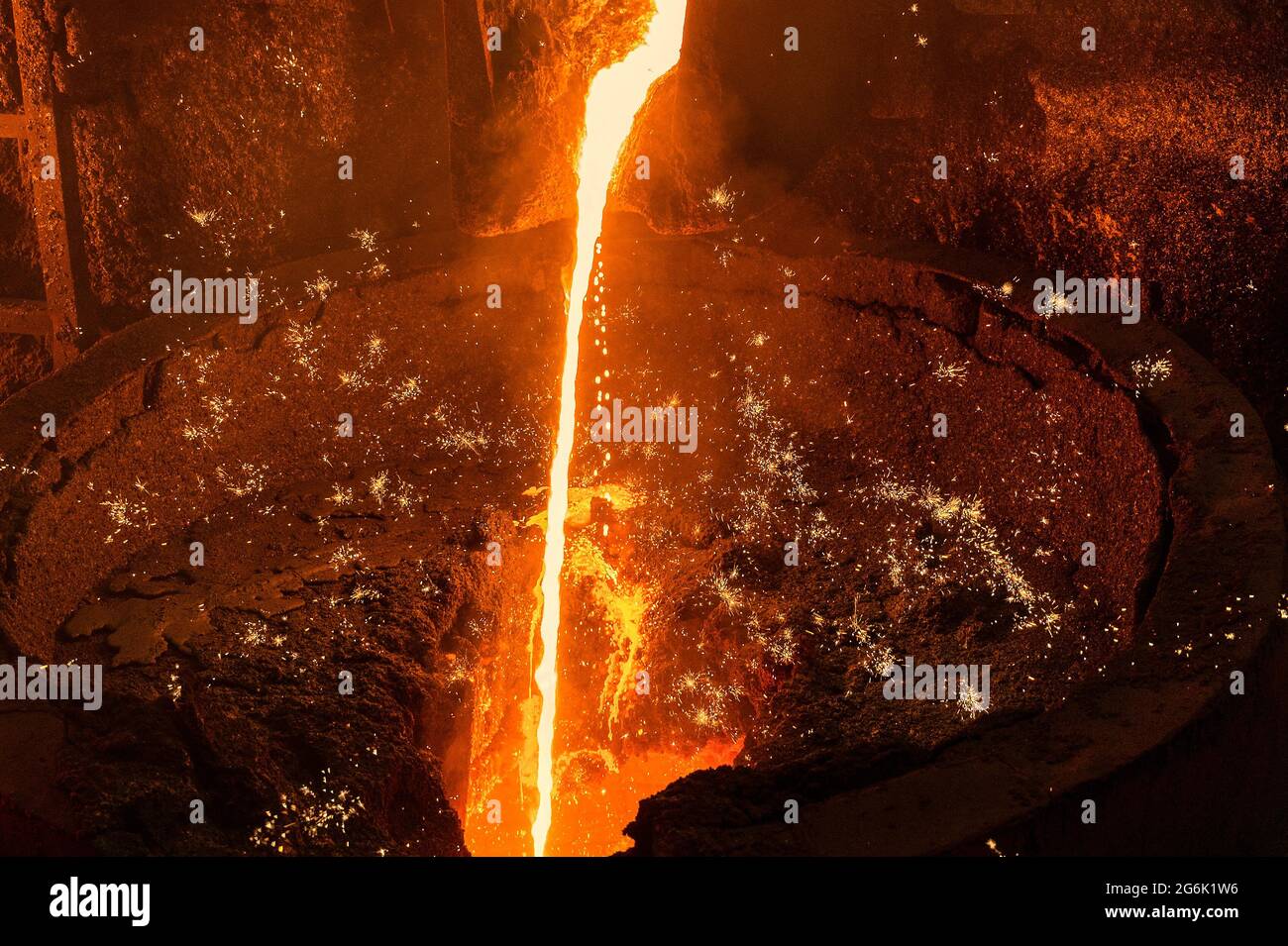 Molten iron flow. Liquid metal is poured into the ladle in a thin ...